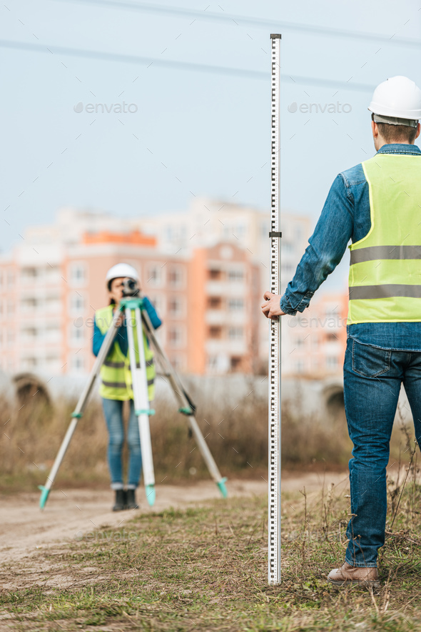 Selective focus of surveyors measuring land with digital level and ...
