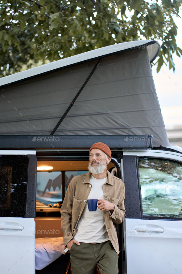 Older man traveler standing near rv camper van drinking coffee enjoying ...