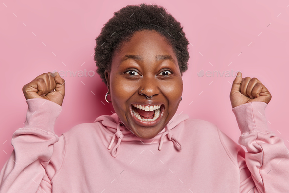 Empowered triumph. Cheerful African woman with short hair shakes ...