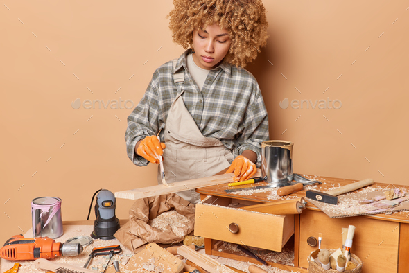 Horizontal shot of professional female woodworker concentrated down ...