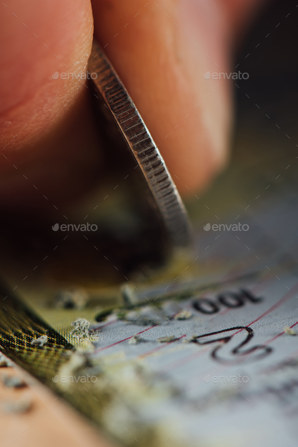 close up view of silver coin in hand of gambler scratching lottery card ...