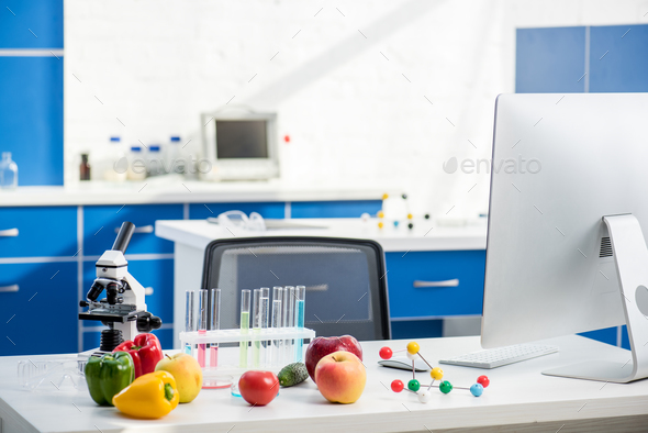 microscope, fruit, vegetables, test tubes and computer on table in lab ...