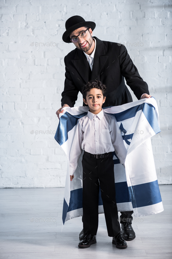 smiling jewish father holding flag of israel and cute son looking at ...