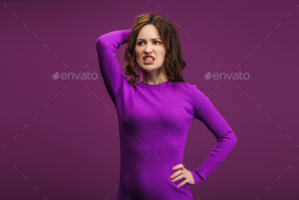 angry woman standing with hand on hip and touching head on purple ...