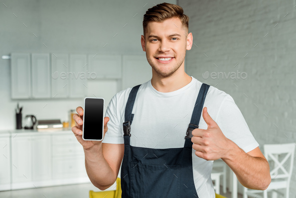 happy installer holding smartphone with blank screen and showing thumb ...