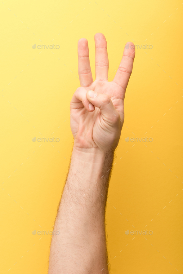 cropped view of man showing three fingers on yellow background Stock ...