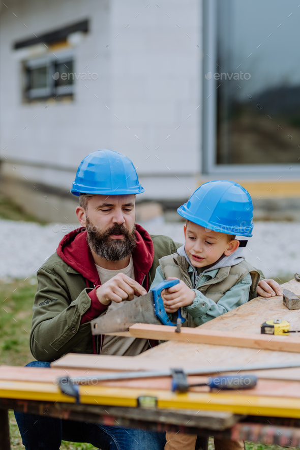 Father and his little son working in front of their unfinished house ...