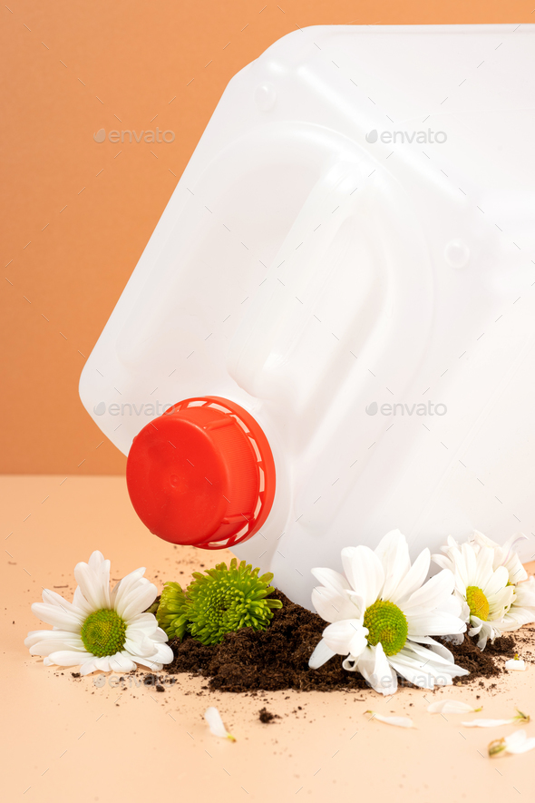 Negative impact on nature. Plastic canister crushes beautiful flowers ...