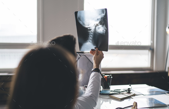 Faceless doctor examining cervical spine x ray image during ...