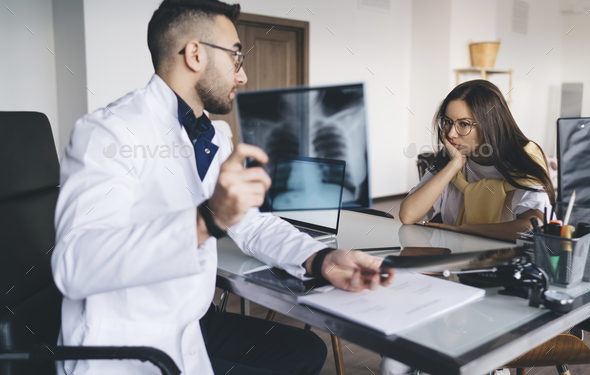 Doctor telling diagnosis to frustrated patient while showing x ray ...