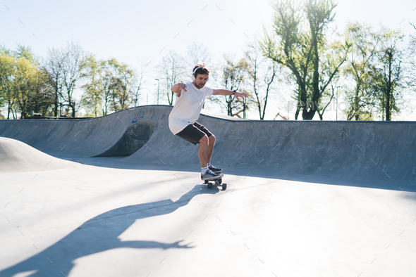 Man riding skateboard on ramp at skate park with arms outstretched ...