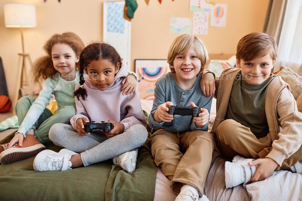Diverse group of happy little children playing video games and having ...