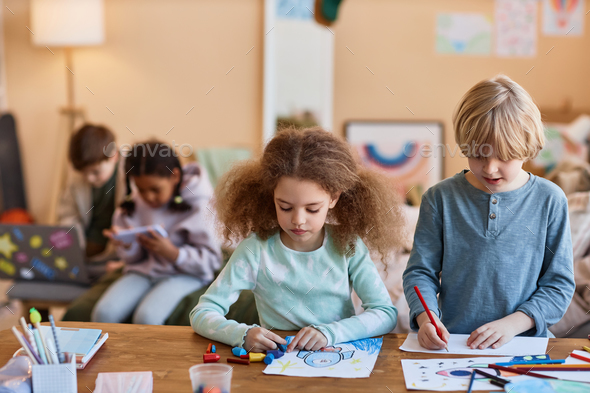 Two kids drawing together during art class Stock Photo by seventyfourimages