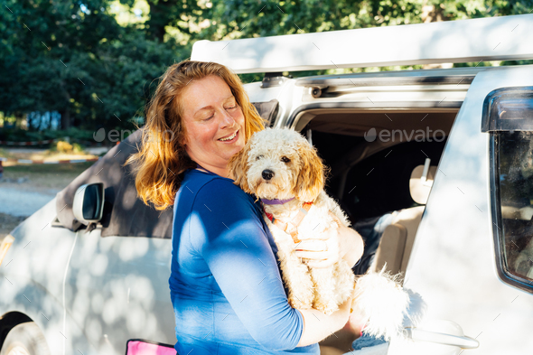 Portrait of middle-aged woman hugging her cockapoo puppy pet while ...