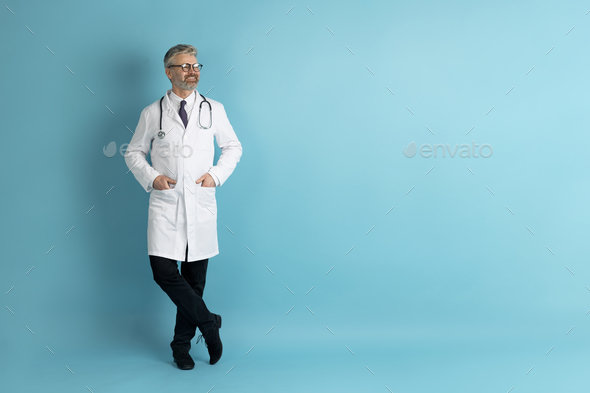 Cheerful grey-haired doctor looking at copy space on blue Stock Photo ...