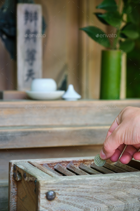 Hand making a offering in wooden offering box or Saisen Box, in ...