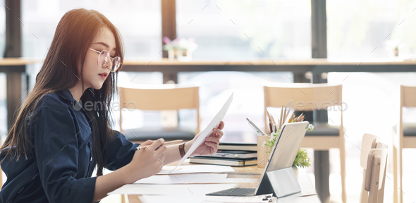 Young female college student using laptop learning online while sitting ...