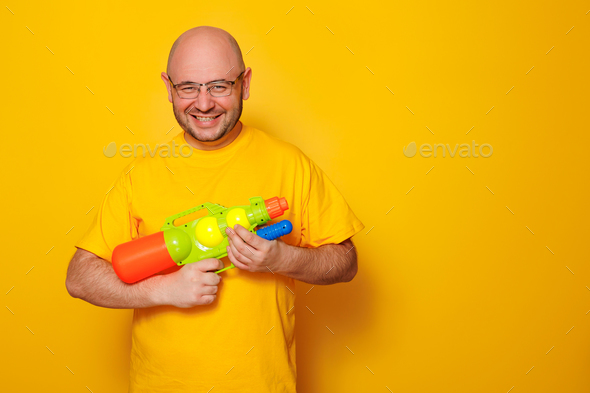 Man holding water gun on yellow background Stock Photo by vladans ...