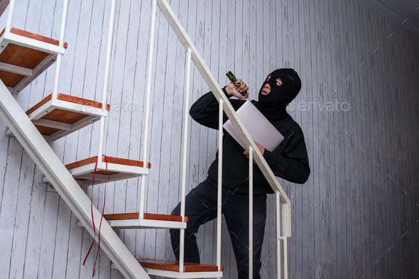 Masked burglar with flashlight stealing laptop Stock Photo by Queenmoonlite