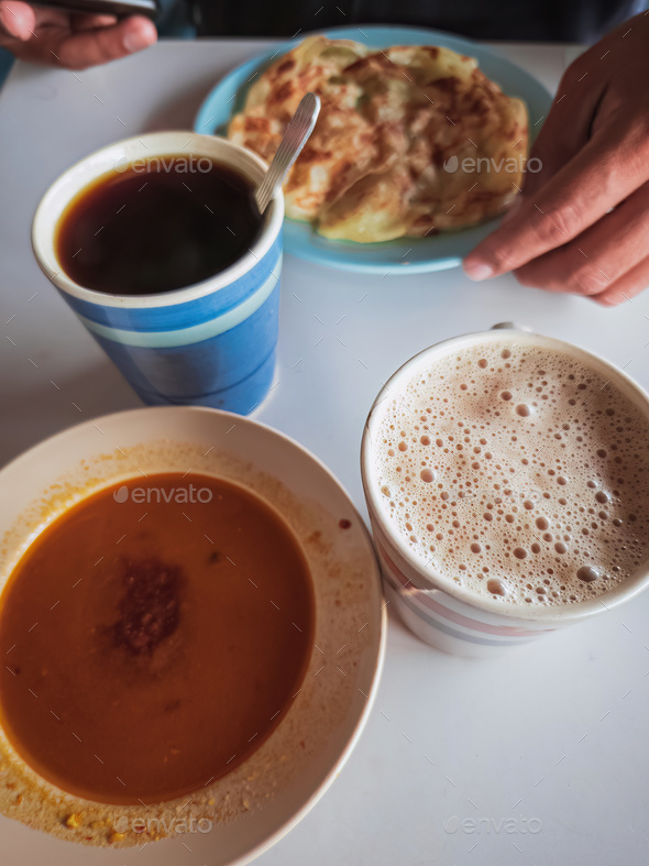 Teh tarik with Roti Canai and black coffee in the background. A staple ...