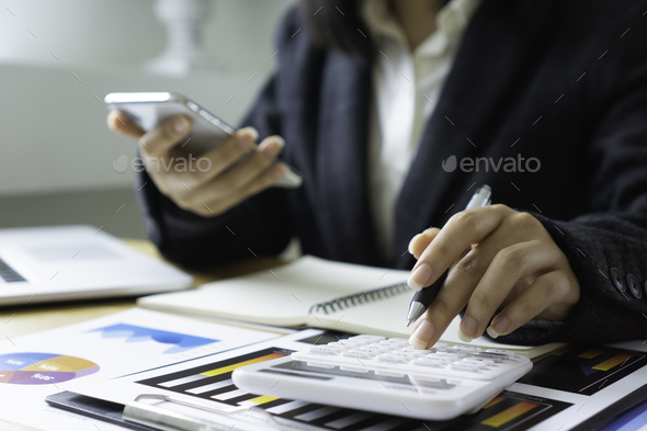 A female office worker is pressing a calculator to calculate sales from ...