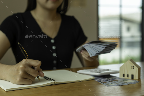 Women are taking notes of income and expenses And counting dollar bills ...