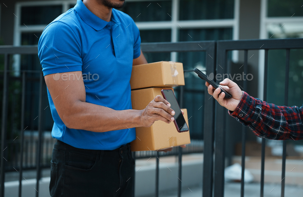 Delivery man handing parcel box to customer, percel box being paid with ...