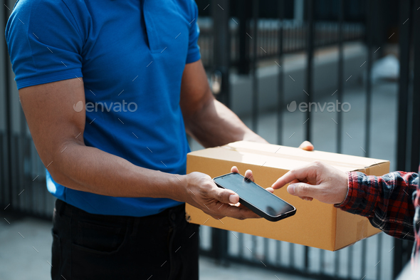 Delivery man handing parcel box to customer, percel box being paid with ...