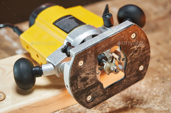 yellow handheld electric router with a decorative cutter lies on its ...