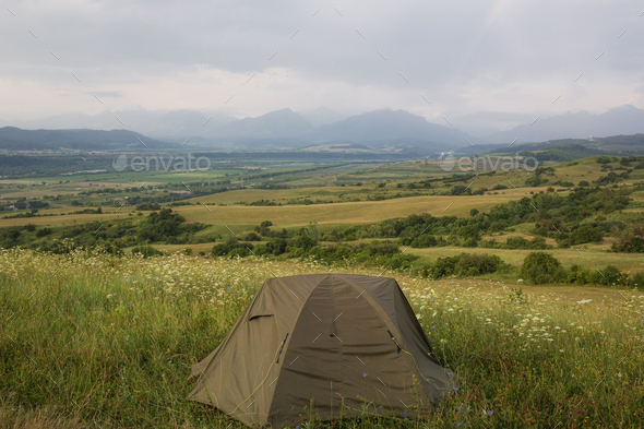 tent in field in summer against backdrop of mountains. relaxation in ...