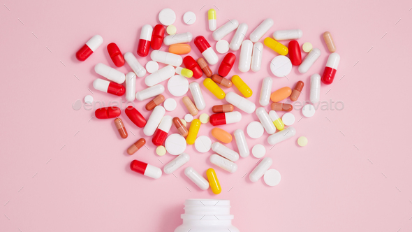 White bottle container with various colorful medication tablets and ...