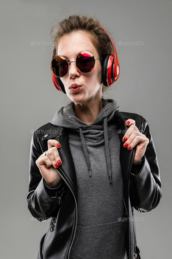 Caucasian girl with rough facial features in a black jacket listen to ...