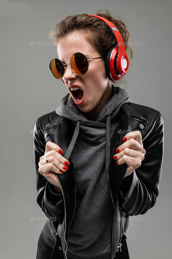 Caucasian girl with rough facial features in a black jacket listen to ...