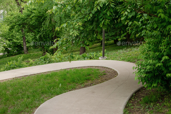 Winding walking concrete path in a summer park. Stock Photo by JulyKo