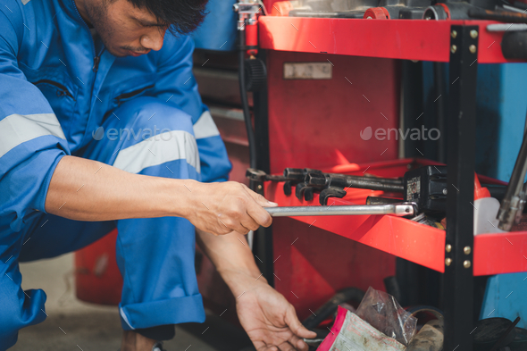 Professional car mechanics searching for auto repair tools in tool ...