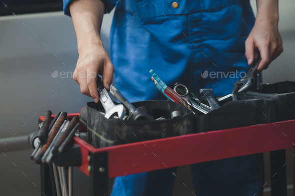 Professional car mechanics searching for auto repair tools in tool ...