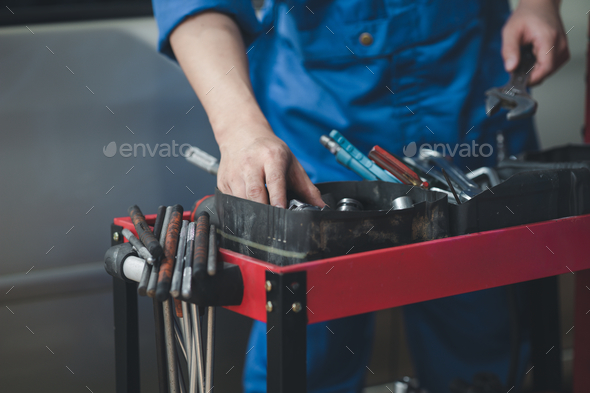 Professional car mechanics searching for auto repair tools in tool ...