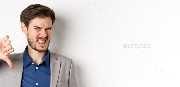 Close-up of disgusted guy in suit grimacing upset, showing thumbs down ...