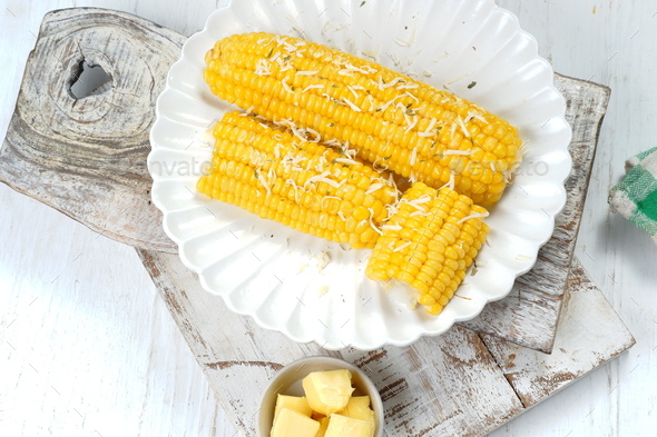 Homemade golden sweet corn cob with butter and cheese on white table ...