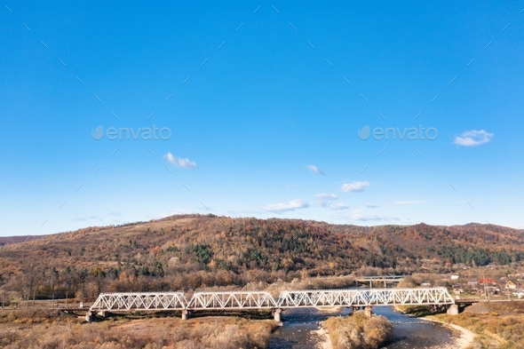 Long railroad bridge over river leading to valley settlement Stock ...