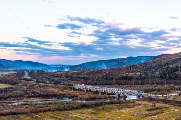 Long railroad bridge over river leading to valley settlement Stock ...