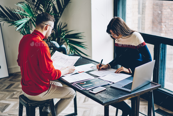 Young male and female partners analyzing documents and checking ...