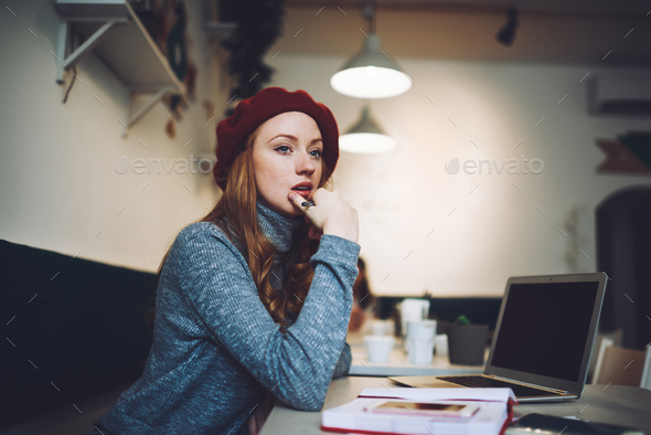 Pensive female touching chin while thinking Stock Photo by GaudiLab