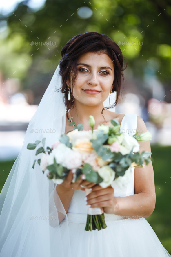 Beautiful bride with wedding bouquet for walk in park. Bride in white ...