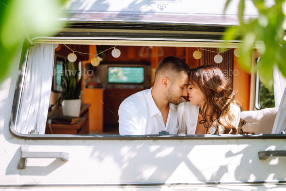 Beautiful wedding couple laugh and kiss relaxing in rv, camping in a ...