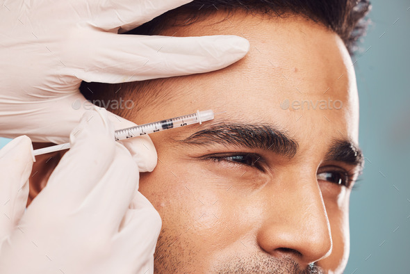 Handsome young indian man receiving a botox injection against a blue ...