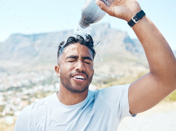 Closeup of a handsome young man standing alone and pouring water on his ...