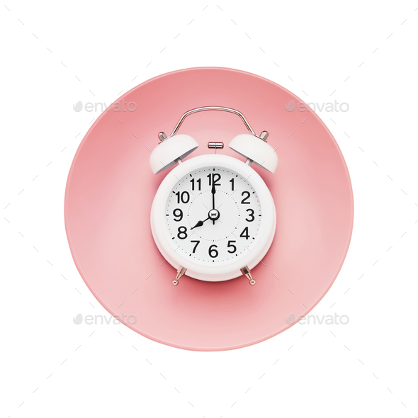 Intermittent fasting concept. White alarm clock on empty pink plate ...