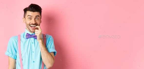 Excited and tempted young guy wants something, biting fingernail with ...