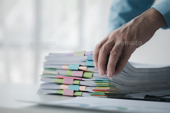 A person in an office with a huge stack of papers, he is a company ...